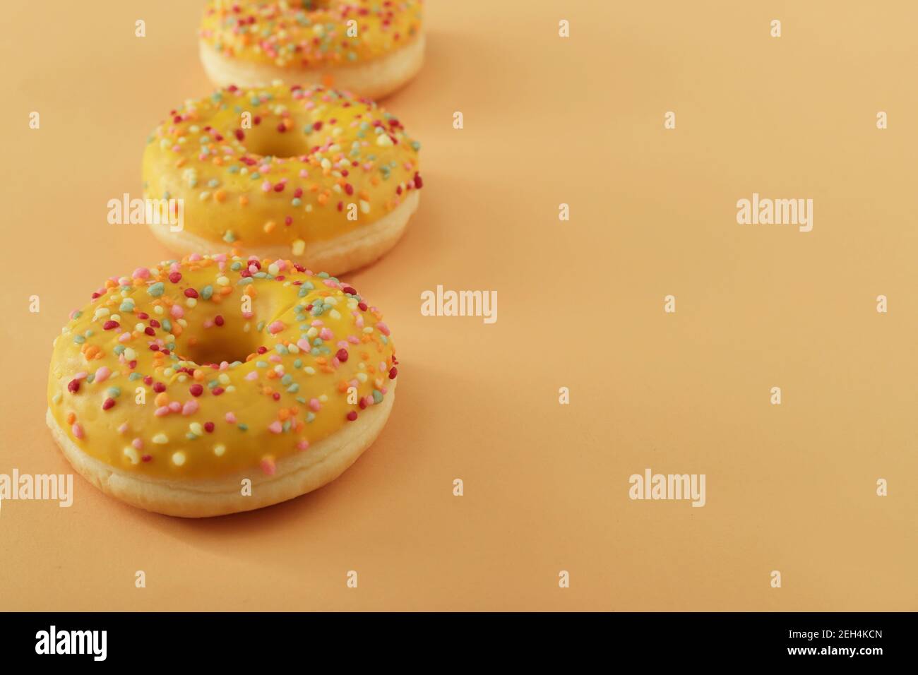 horizontal photo of doughnuts to the right on a pastel orange ...