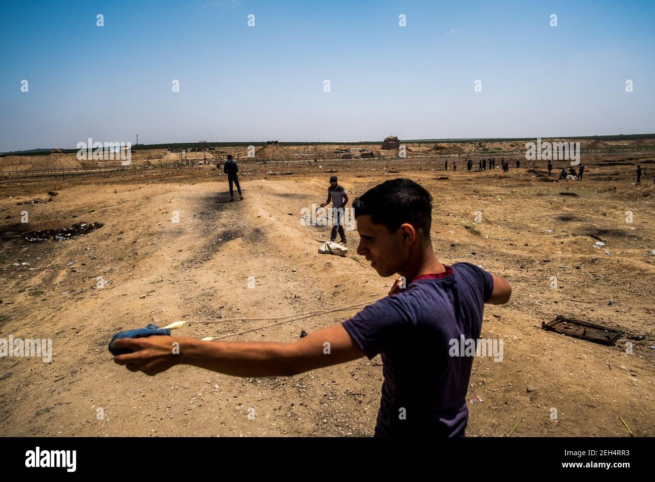 A demonstrator prepares to use his slingshot to throw stones at the ...