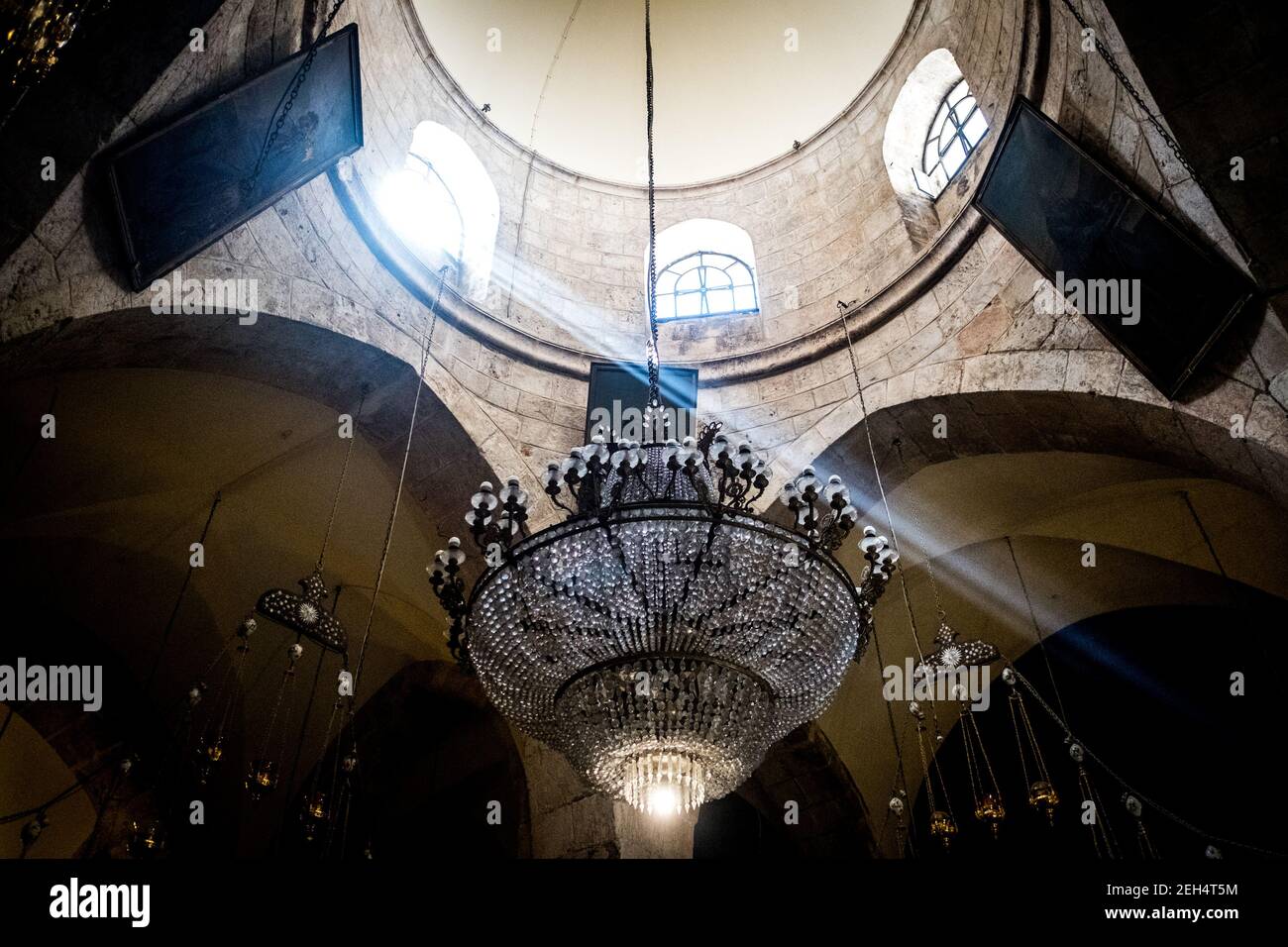 A chandelier illuminated by a ray of light hangs from the ceiling of ...