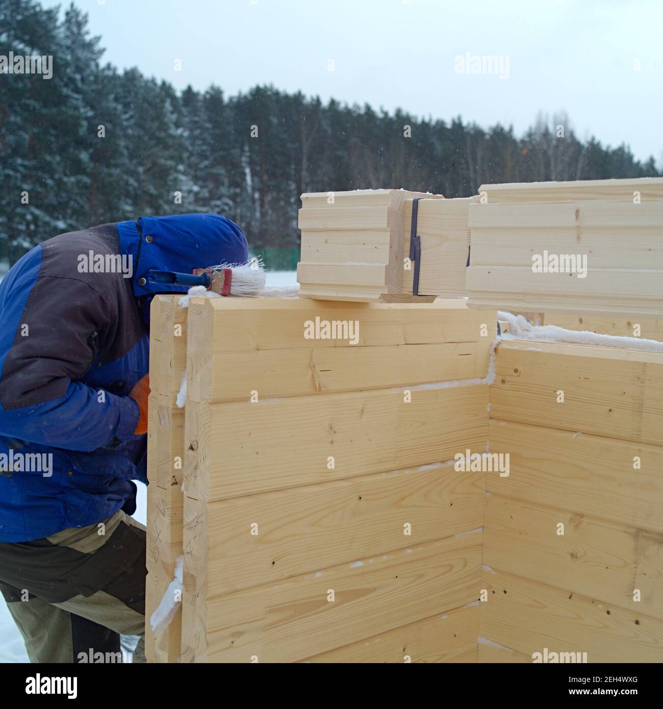 A carpenter working outdoor in a nasty snowy weather, winter scene ...