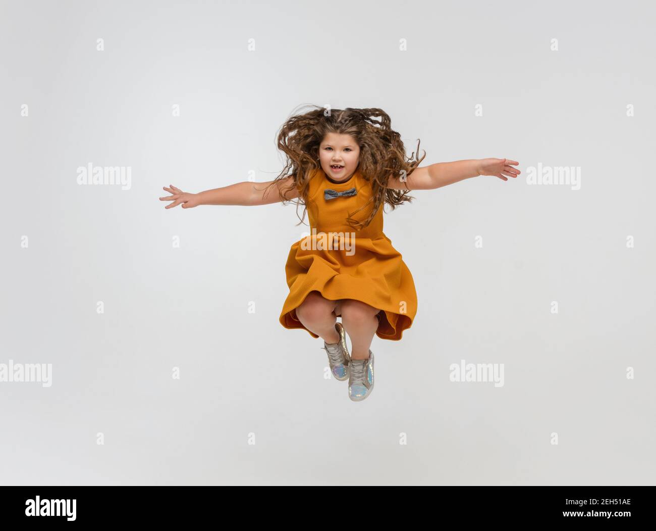 Jumping high. Happy, smiley little caucasian girl isolated on white ...