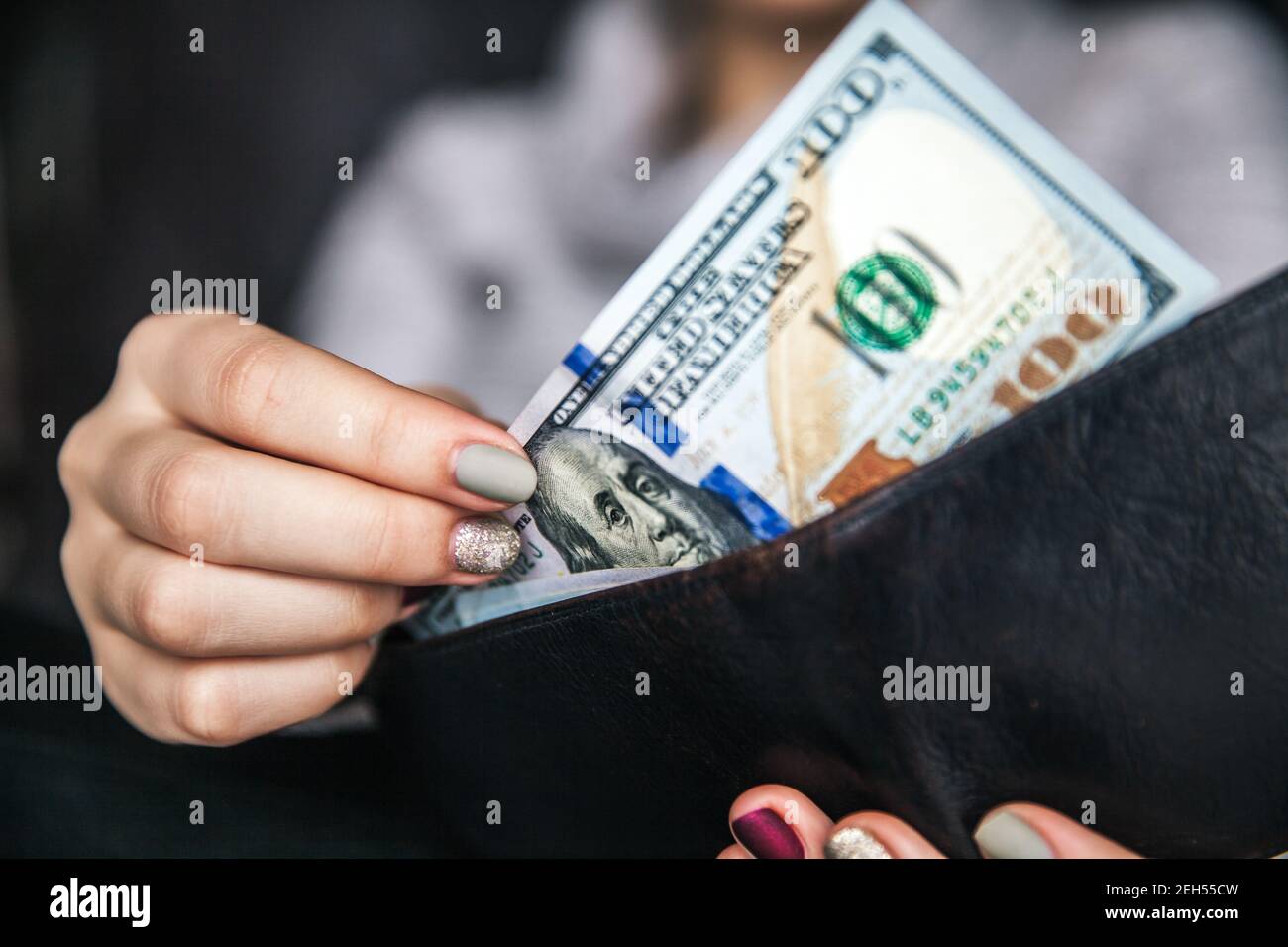 In the women's hands is the brown leather wallet with a wad of hundred ...