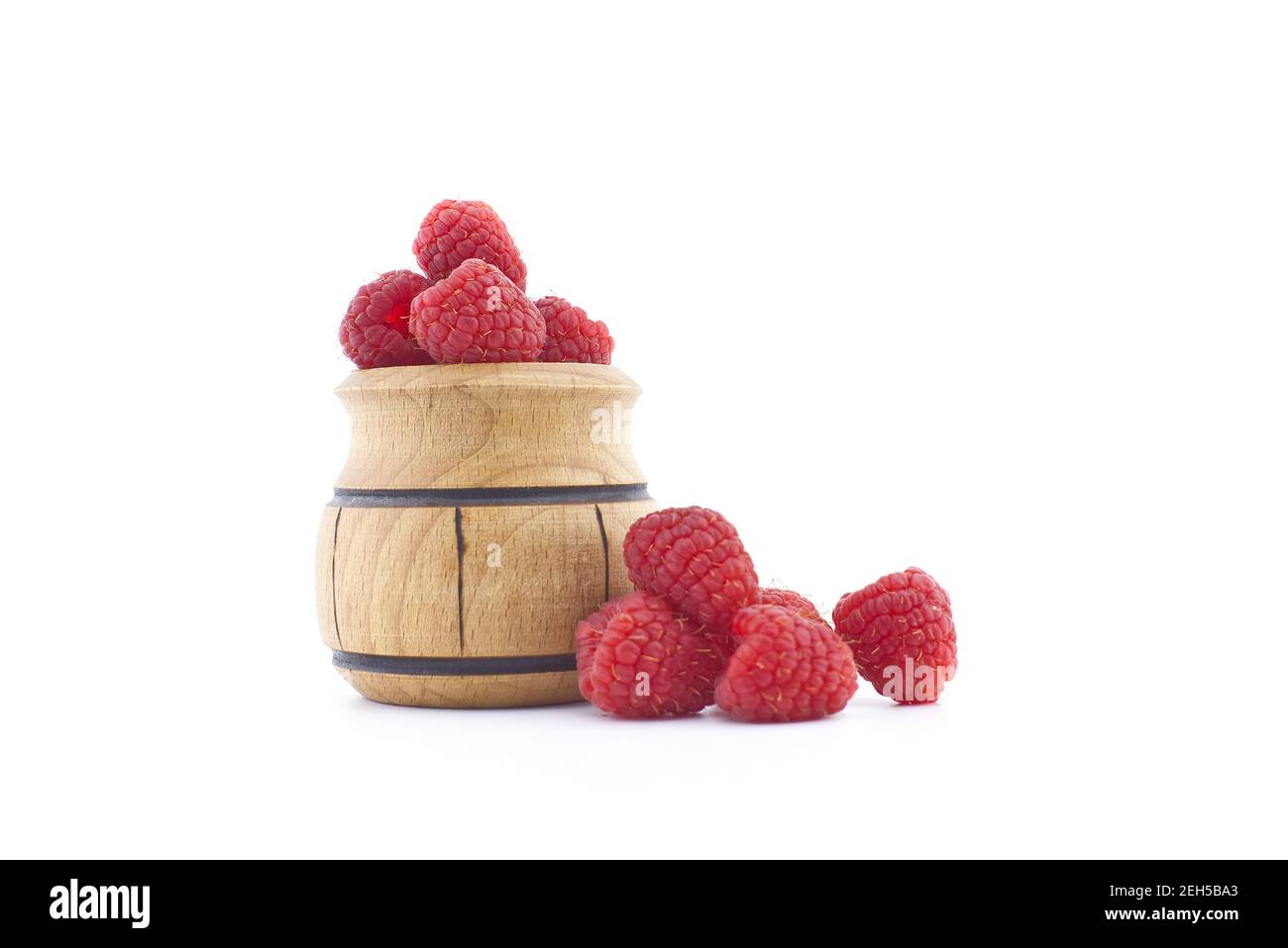 Pile of red ripe raspberry berries and a small wooden pot isolated on ...