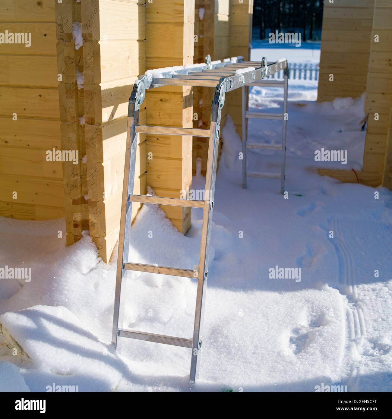 Expandable ladder placed on the snow for carpentry works, winter sunny ...