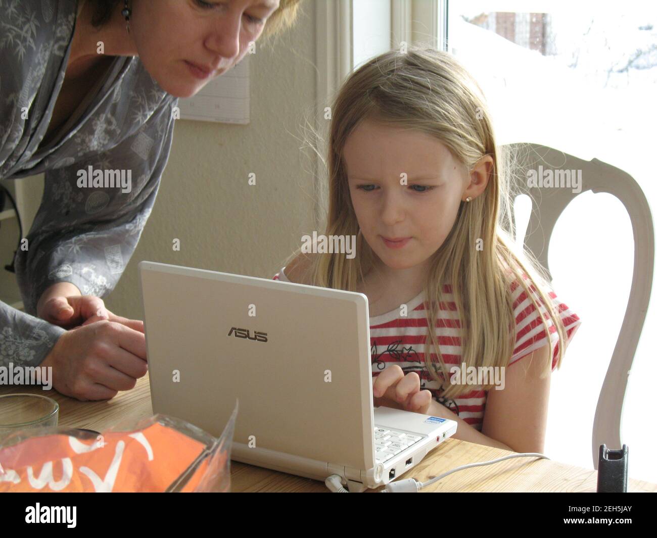 Mother helping young girl to use a computer Photo: Bo Arrhed Stock ...
