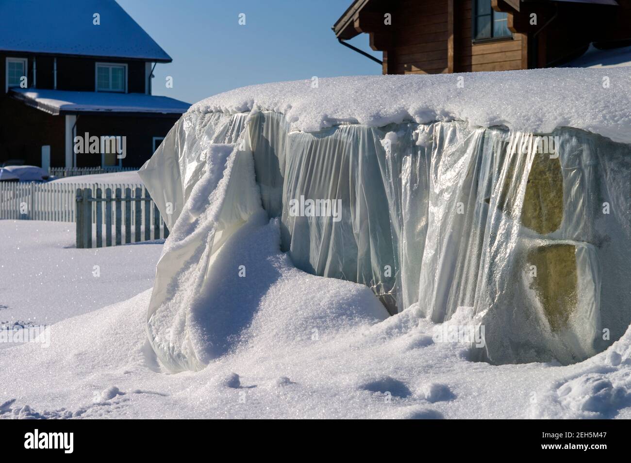 Packs of insulation under snow, new houses in the background, winter ...