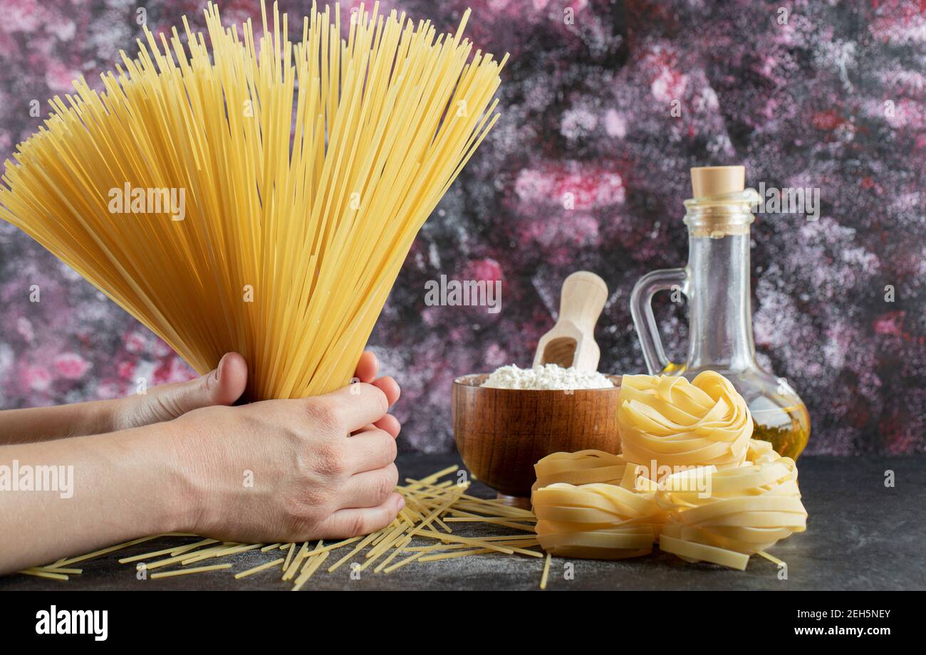 Woman hands holding spaghetti on colorful background with oil and flour ...