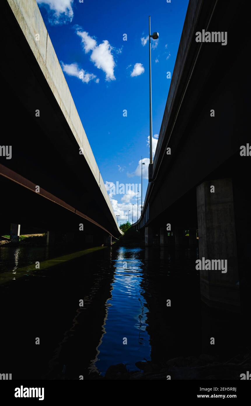 Freeway Bridges over a river showing a bright blue sky reflected in the ...