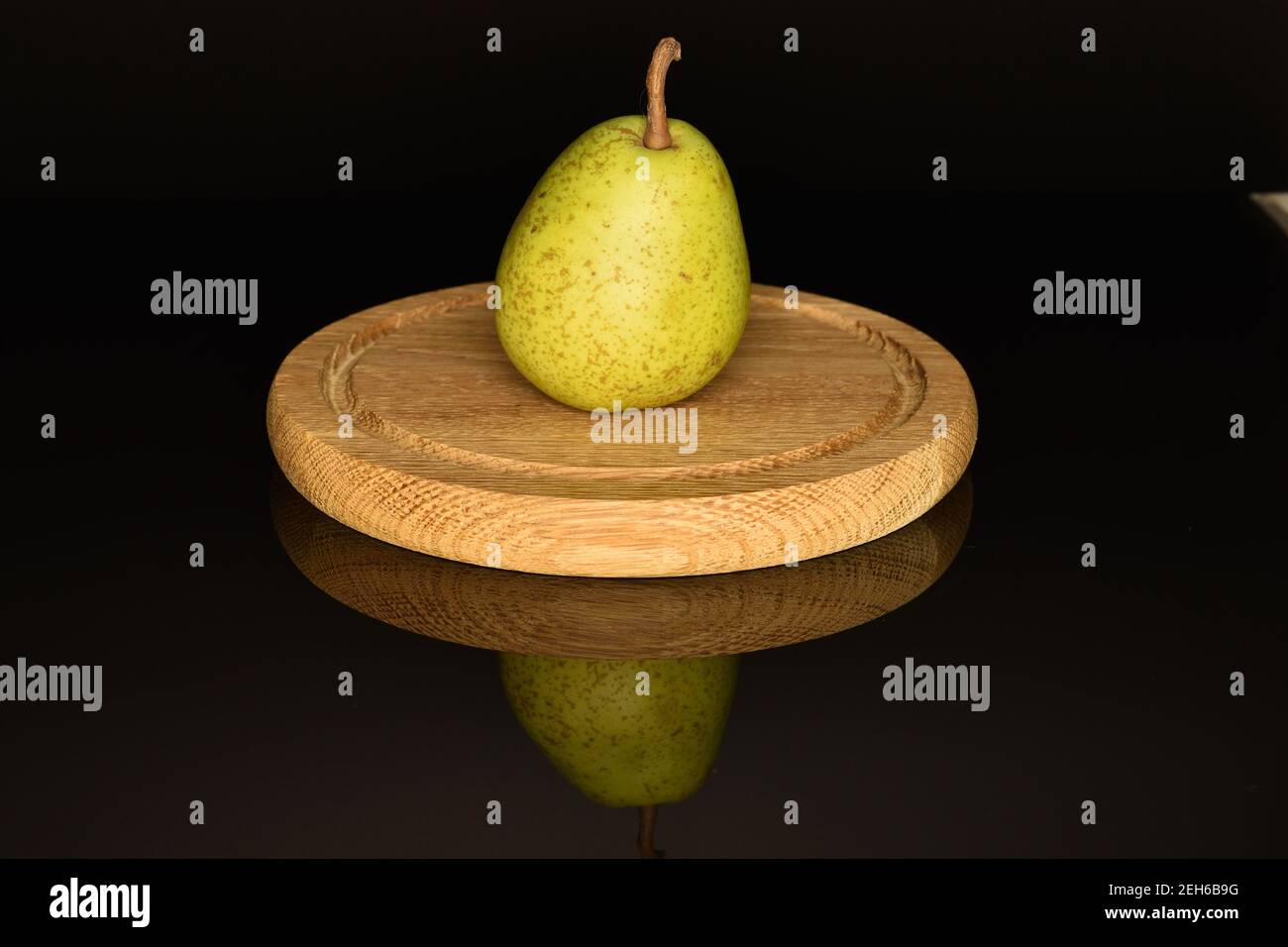 One whole ripe juicy tasty pear Lucas lies on a round wooden tray, on a ...
