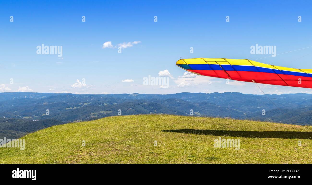 Wide-angle lens shot of a colorful hang glider's wing on a grassy ...