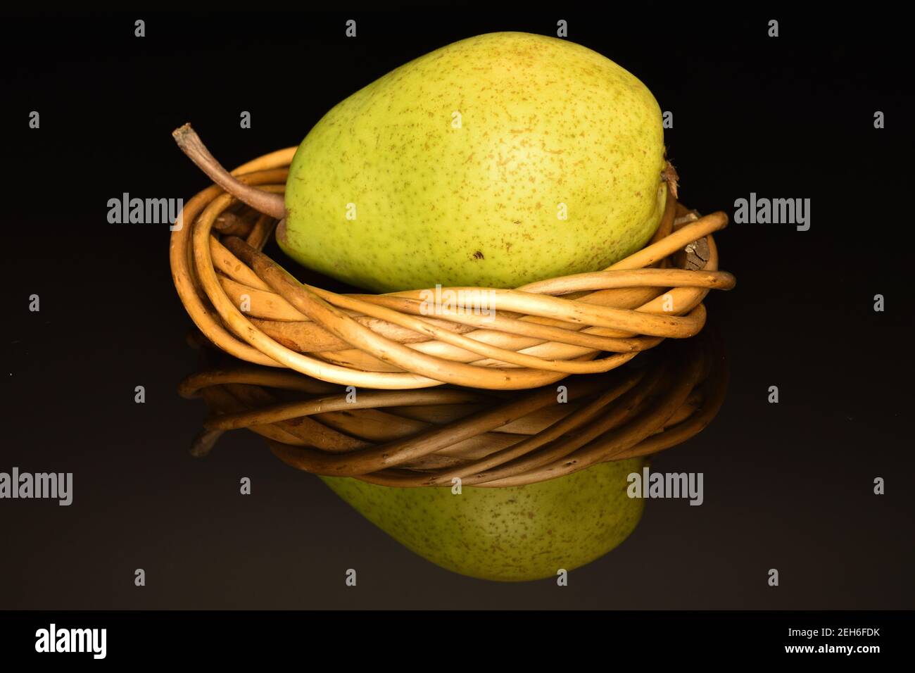 One whole ripe juicy tasty pear Lucas lies in a wicker vine ring, on a ...