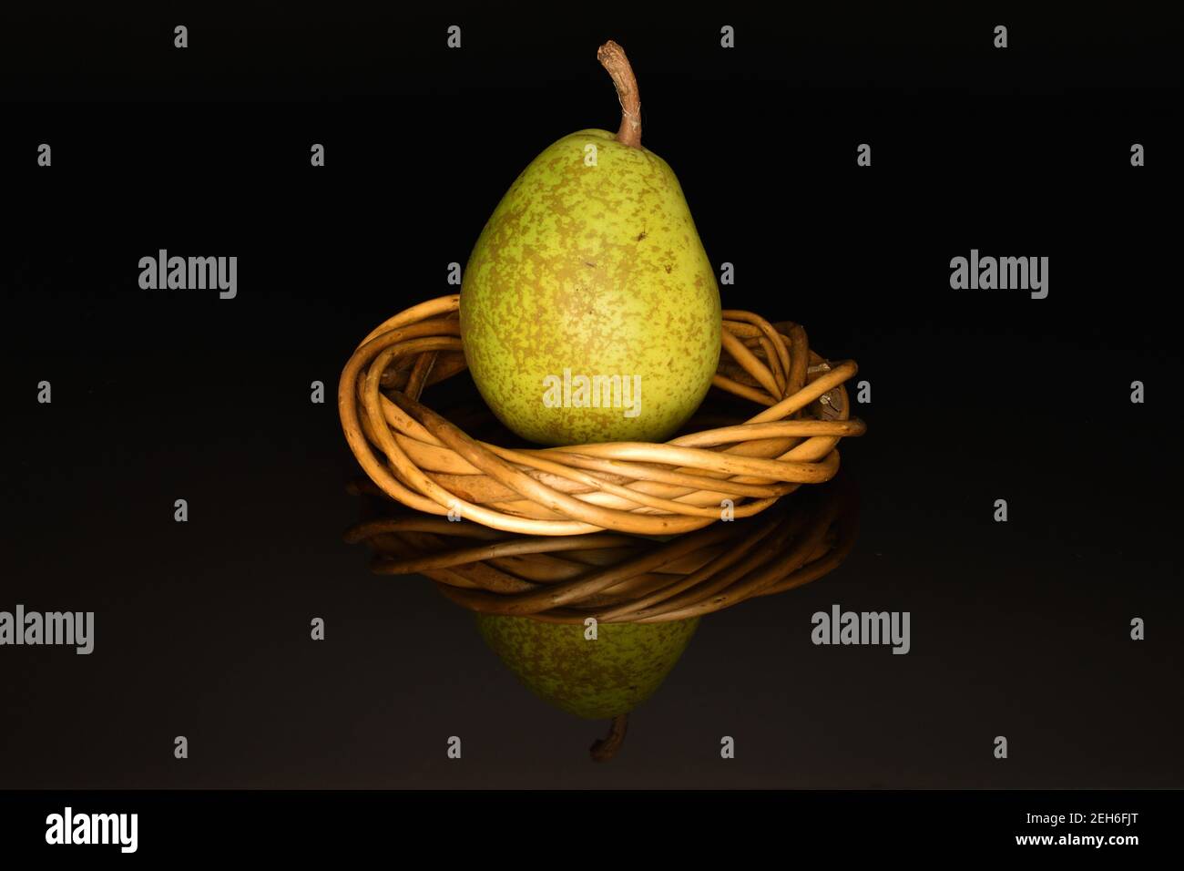 One whole ripe juicy tasty pear Lucas lies in a wicker vine ring, on a ...
