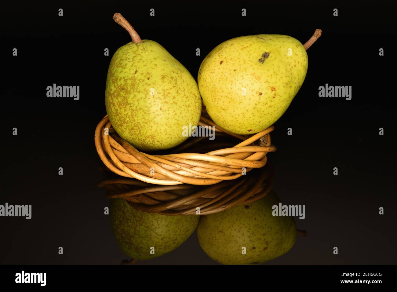 Two whole ripe juicy tasty Lucas pears lie on a ring of wicker vines ...