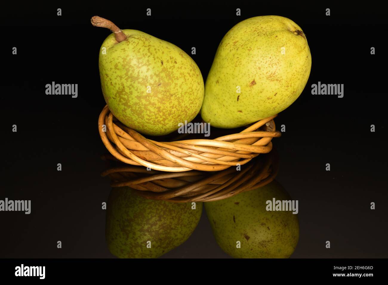 Two whole ripe juicy tasty Lucas pears lie on a ring of wicker vines ...