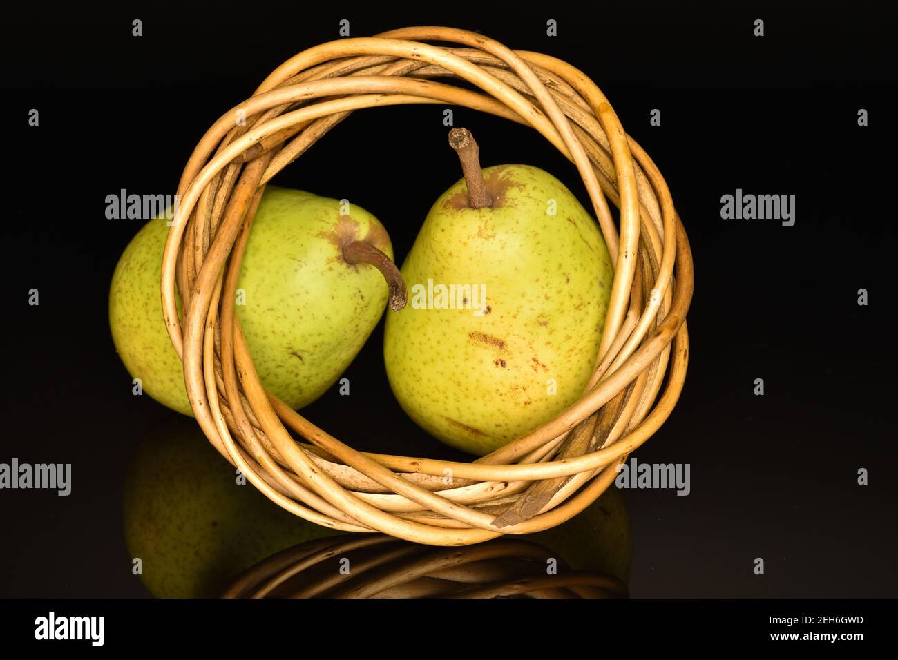 Two whole ripe juicy tasty Lucas pears lie on a ring of wicker vines ...