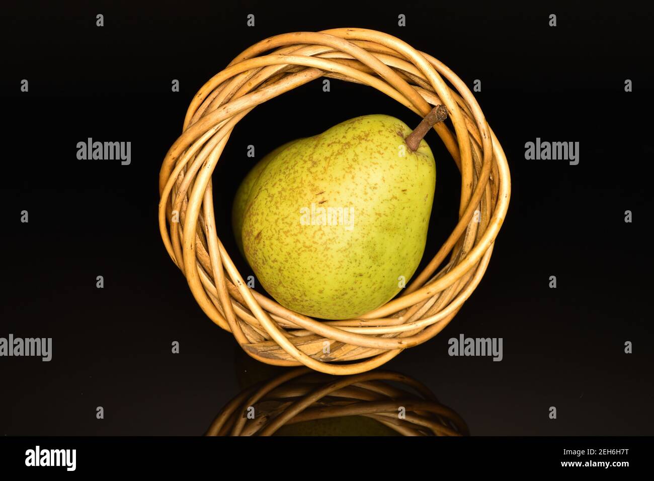 One whole ripe juicy tasty pear Lucas lies in a wicker vine ring, on a ...