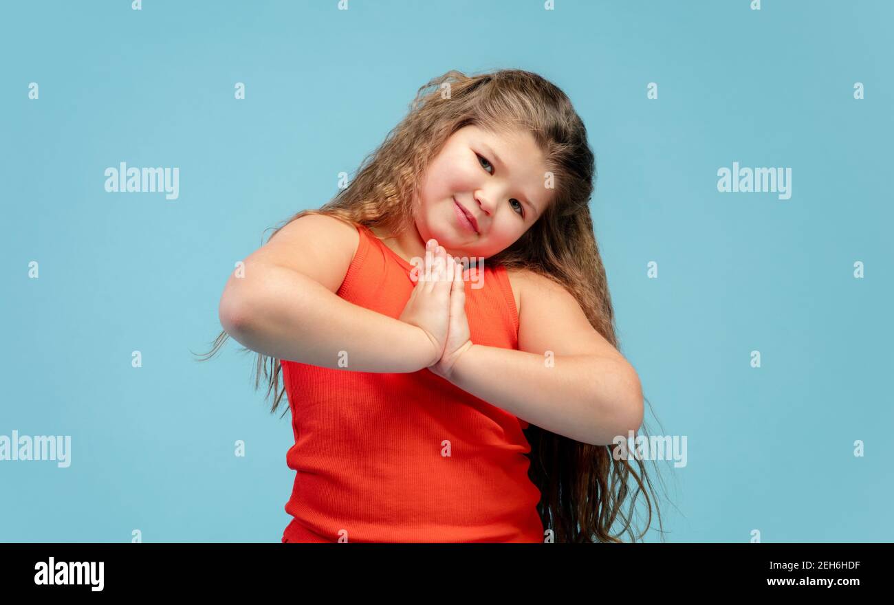 Hopeful. Happy, smiley little caucasian girl isolated on blue studio ...