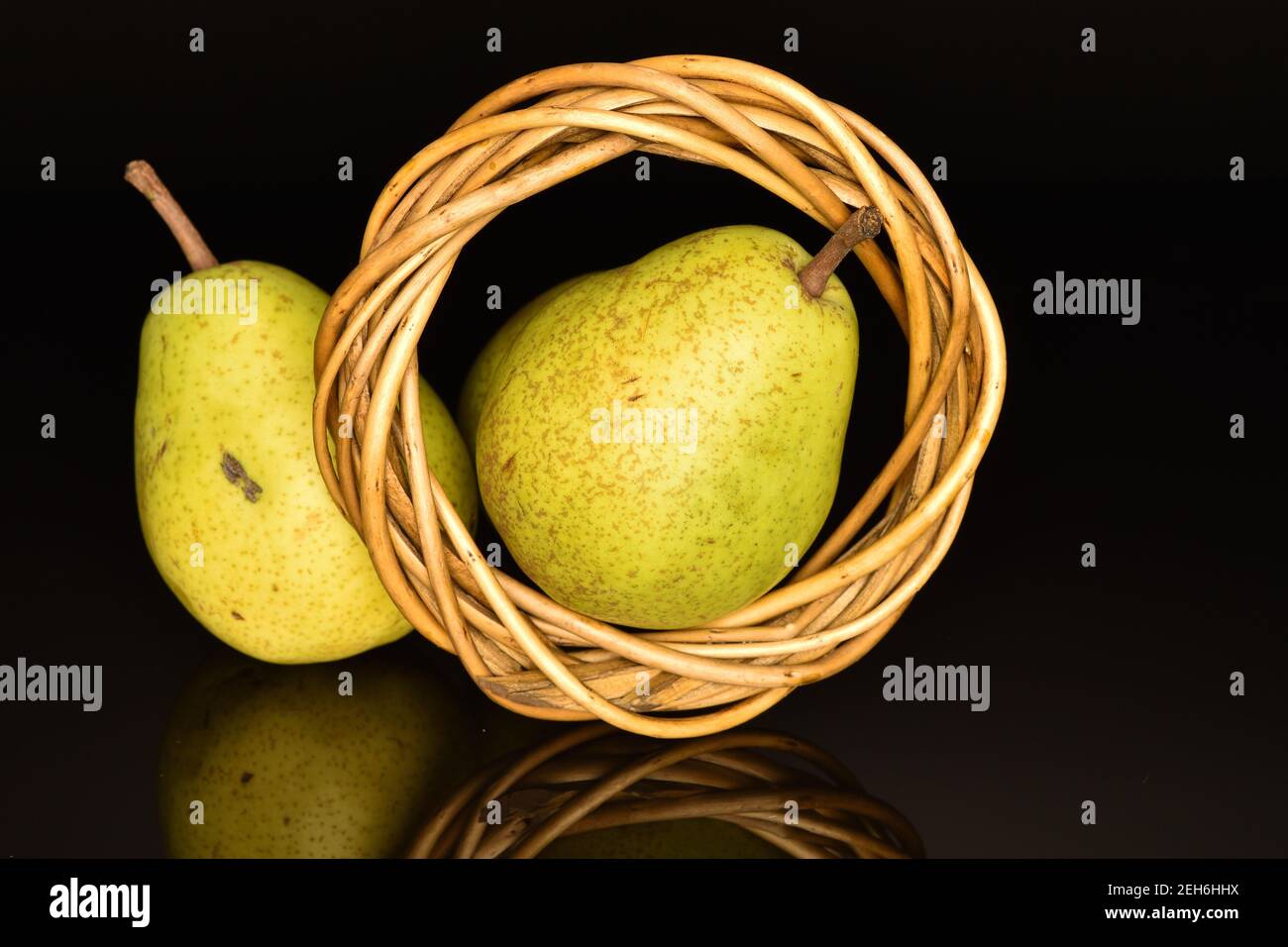 Two whole ripe juicy tasty Lucas pears lie on a ring of wicker vines ...