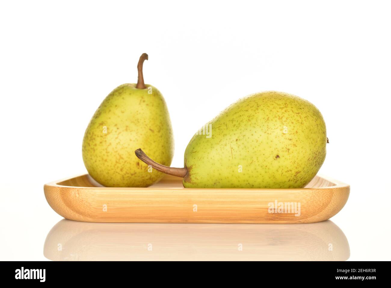 One whole ripe juicy tasty pear Lucas lies on a bamboo tray, on a white ...