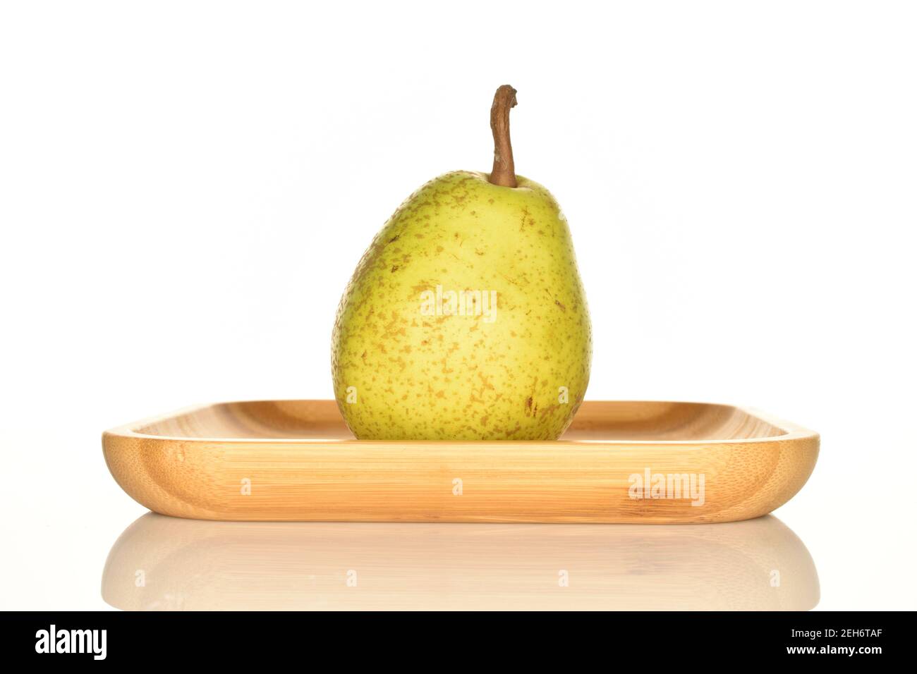 One whole ripe juicy tasty pear Lucas lies on a bamboo tray, on a white ...