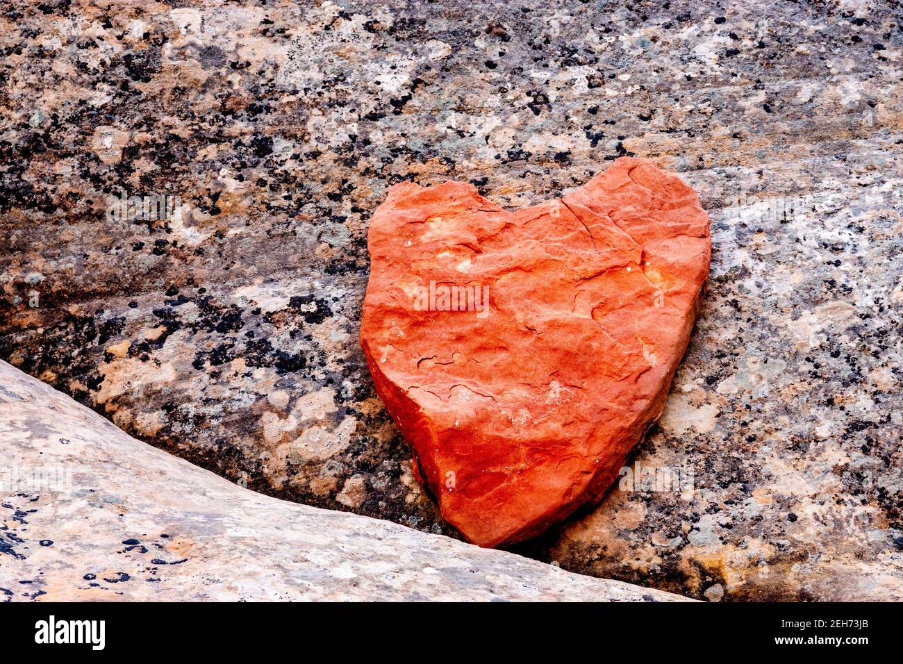 Red heart shape rock laying on granite rock. Valentine card appropriate ...
