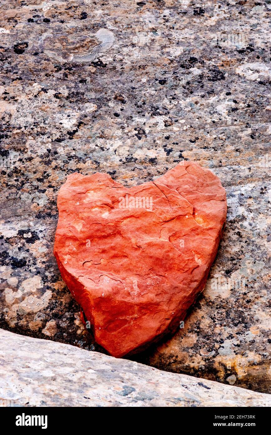 Red heart shape rock laying on granite rock. Valentine card appropriate ...