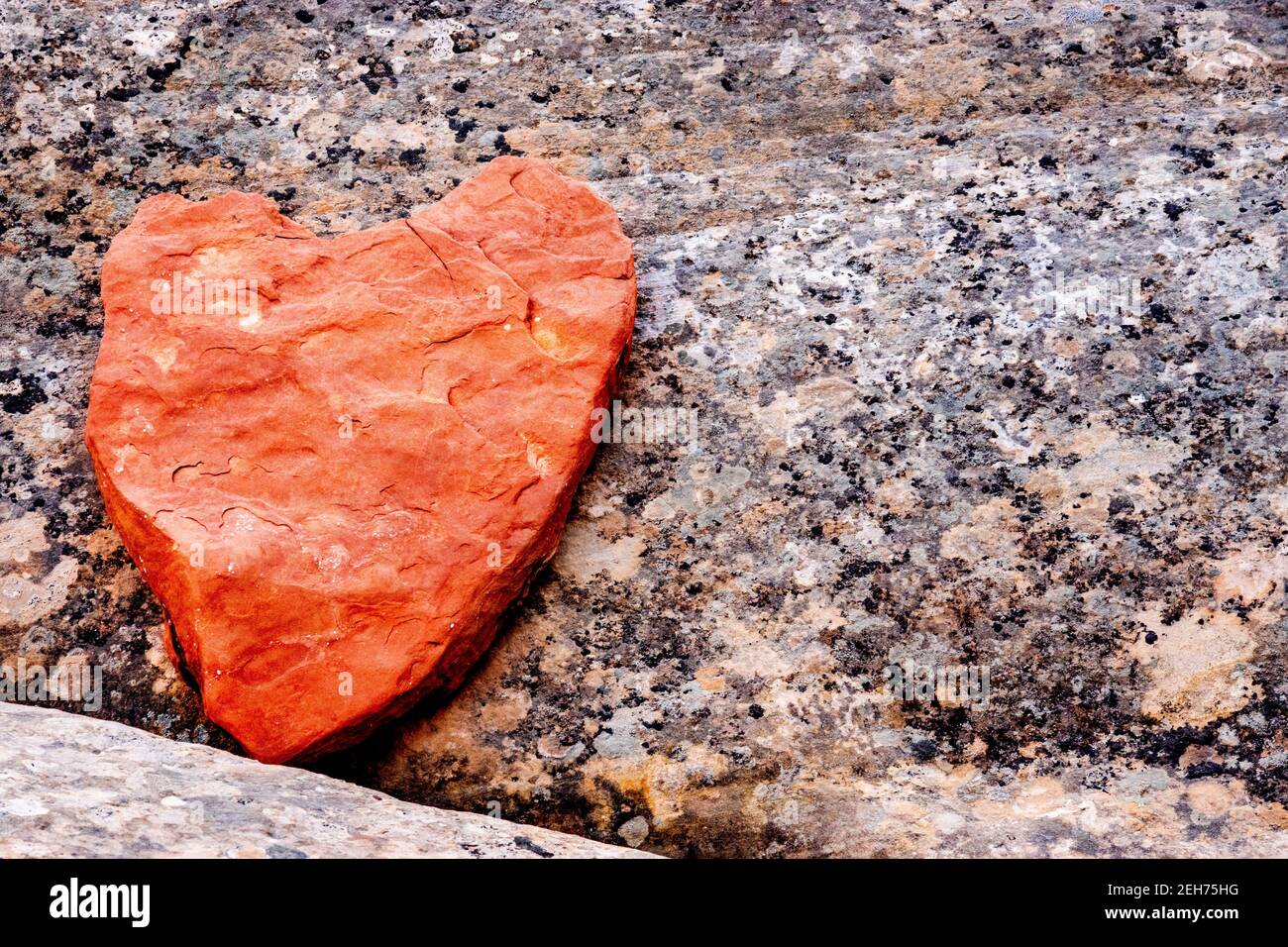 Red heart shape rock laying on granite rock. Valentine card appropriate ...