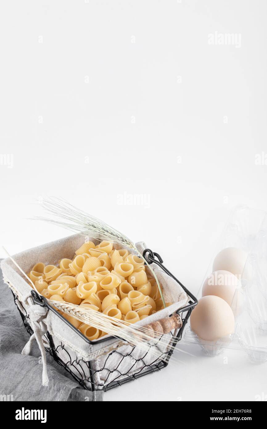 Basket of raw pasta and eggs in container on white surface Stock Photo ...