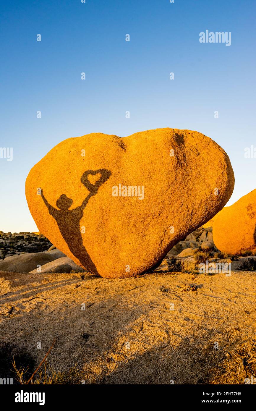Heart shaped boulder with shadow of man holding a heart wreath. In ...