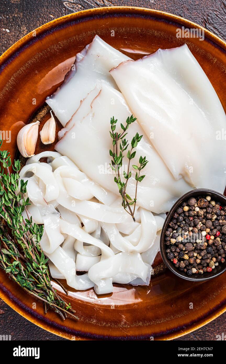 Sliced raw rings Calamari in a rustic plate with rosemary. Dark ...