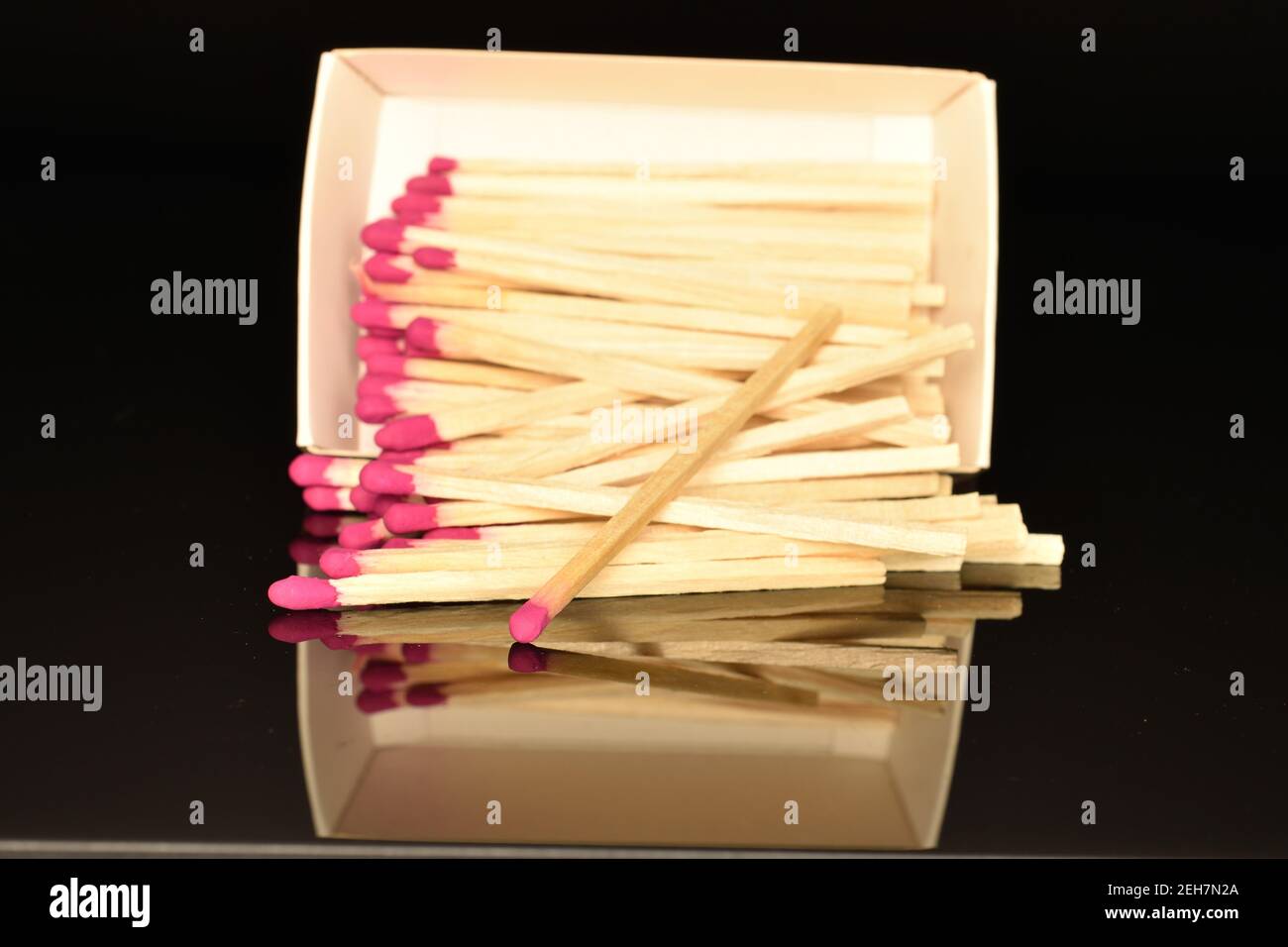 Several wooden matches lie in a white paper box on a black background ...