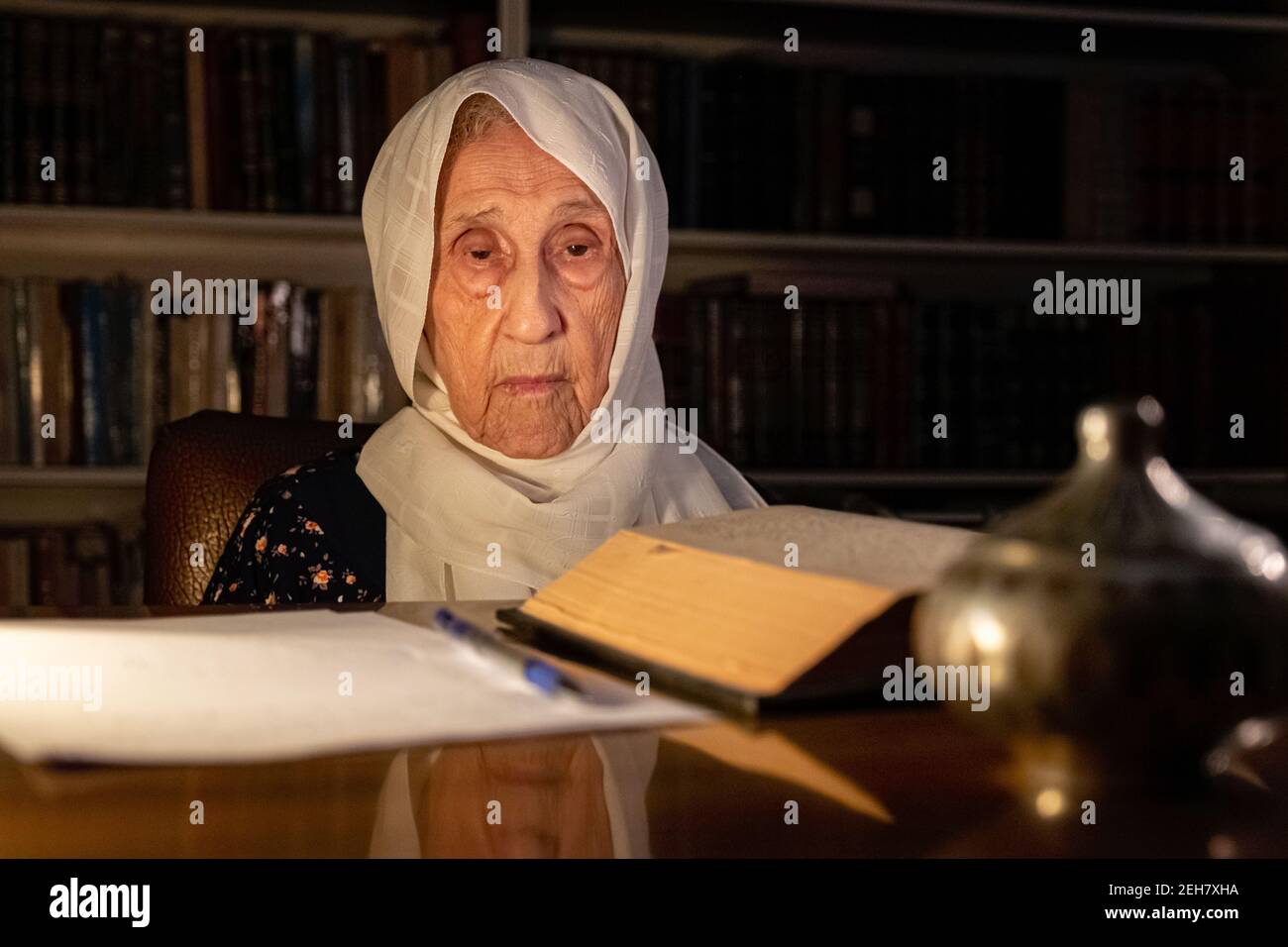 Old lady reading books in dark room with candles light and writing down ...