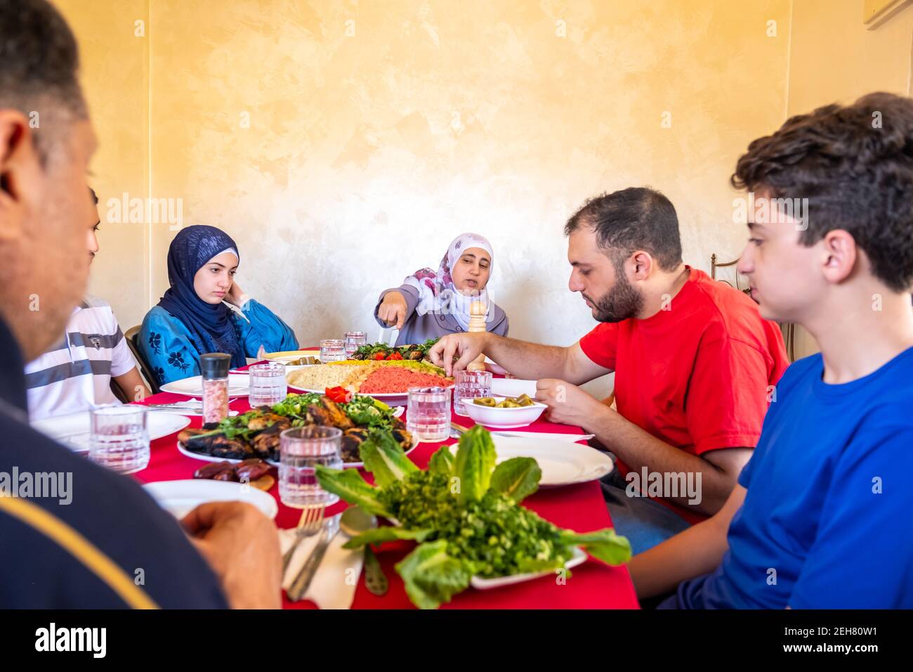 Happy arabic muslim family eating together in a family meeting for ...
