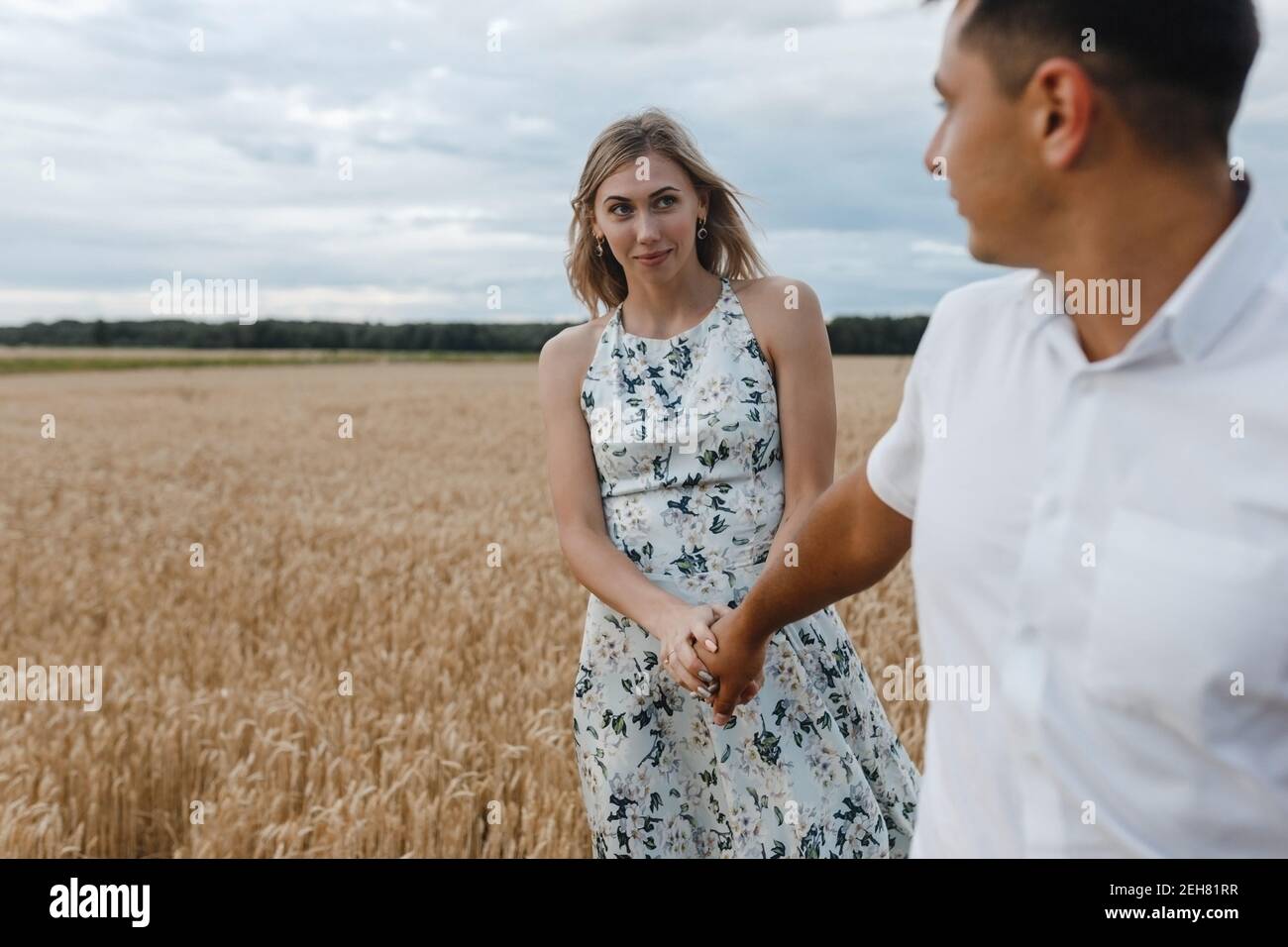 Young couple holding hands and walking on the wheat fild. Love story ...