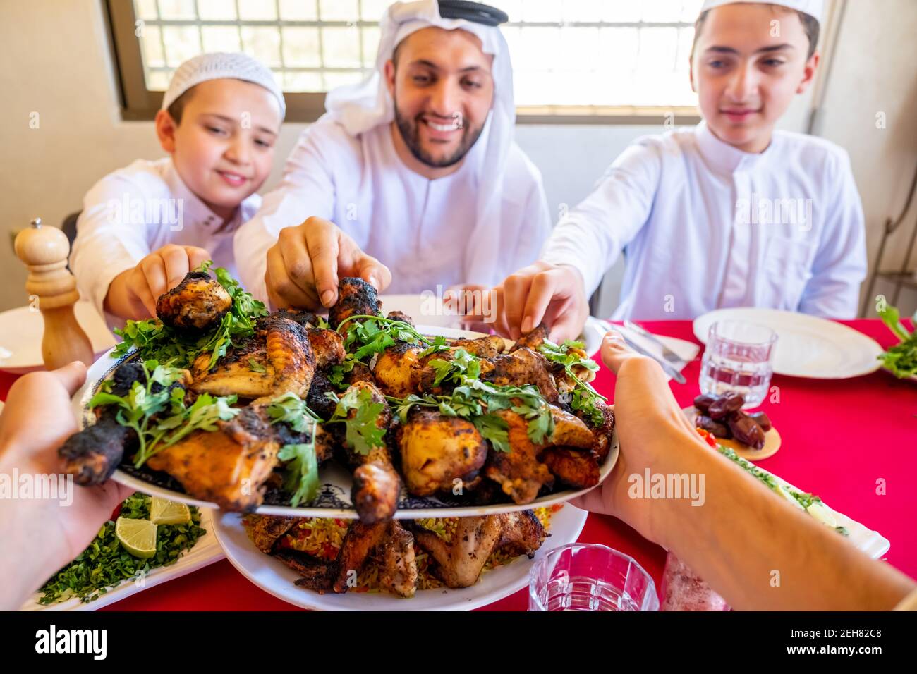 Arabic muslim family being picking chicken from plate being served for ...