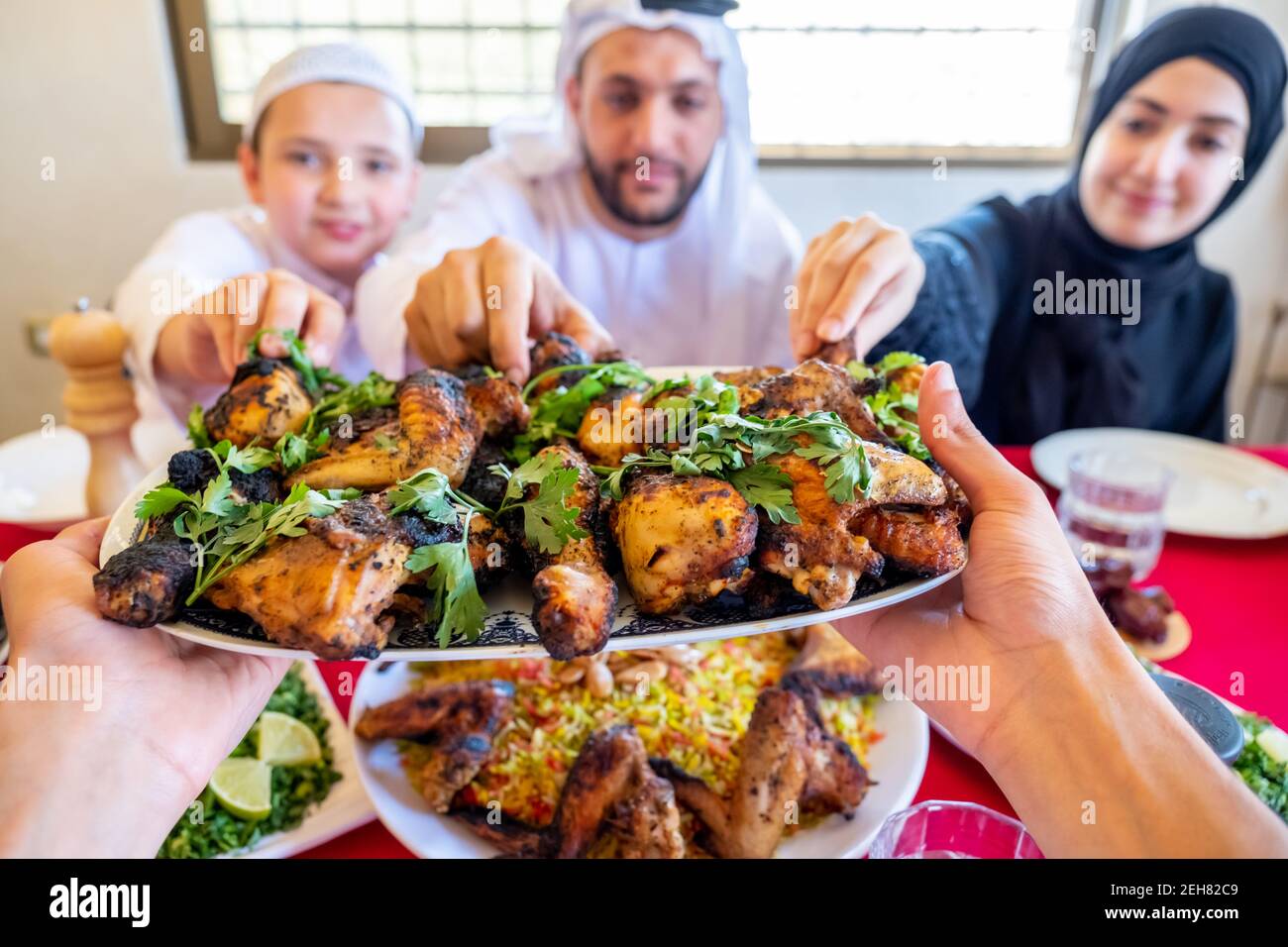 Arabic muslim family being picking chicken from plate being served for ...