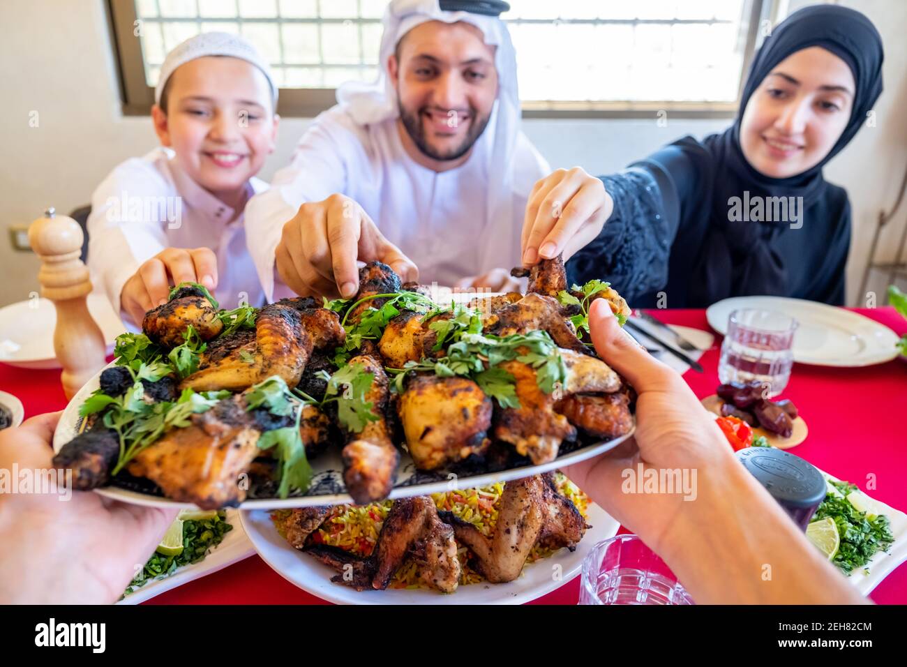Arabic muslim family being picking chicken from plate being served for ...