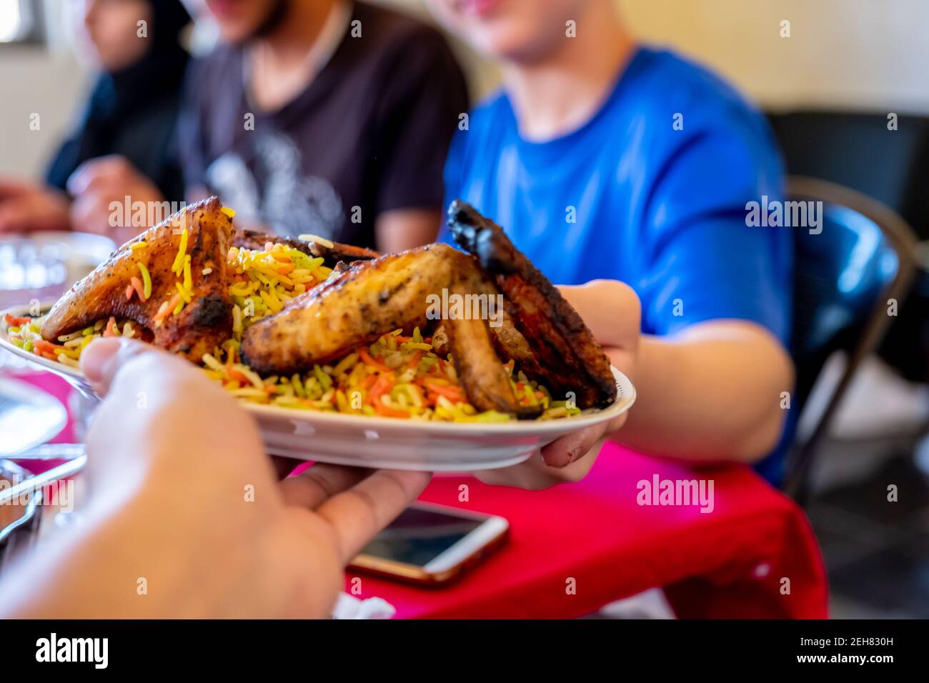 Arabic guy giving plate to his brother Stock Photo - Alamy