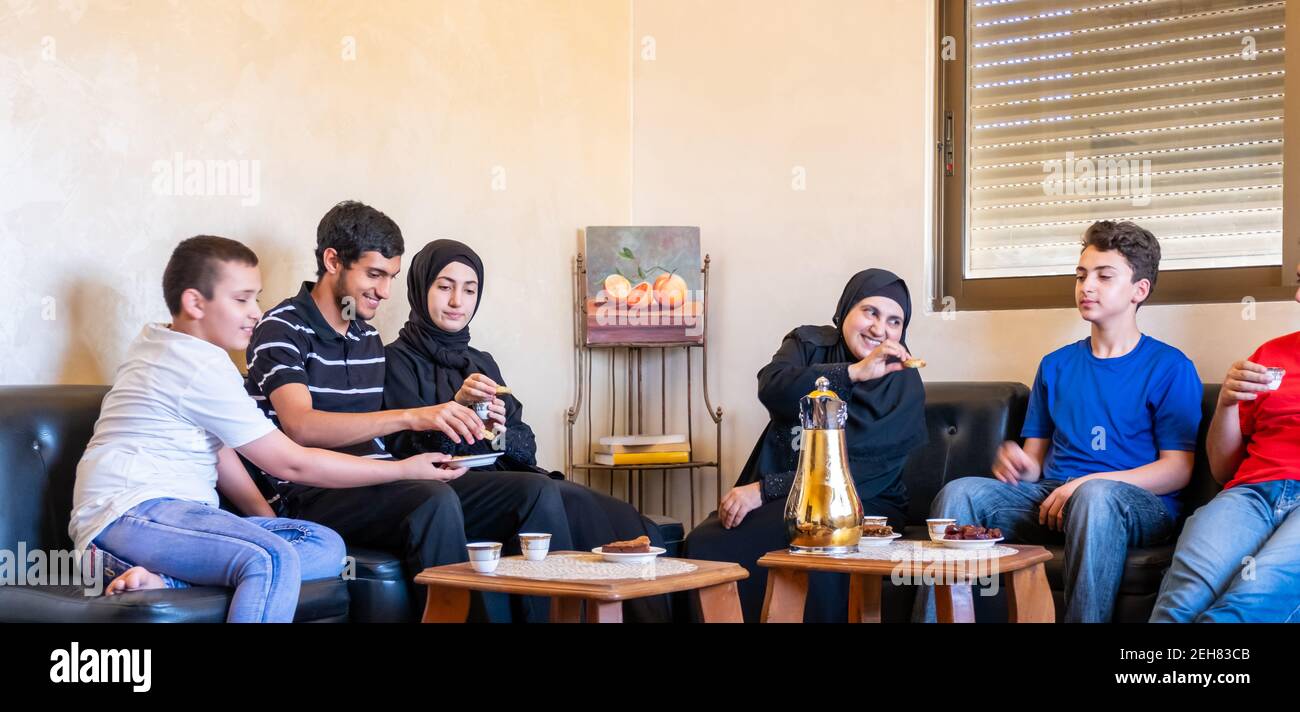 Happy Arabic family sitting together enjoying Arabic coffee and sweets ...