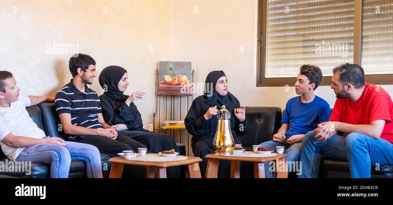 Happy Arabic family sitting together enjoying Arabic coffee and sweets ...