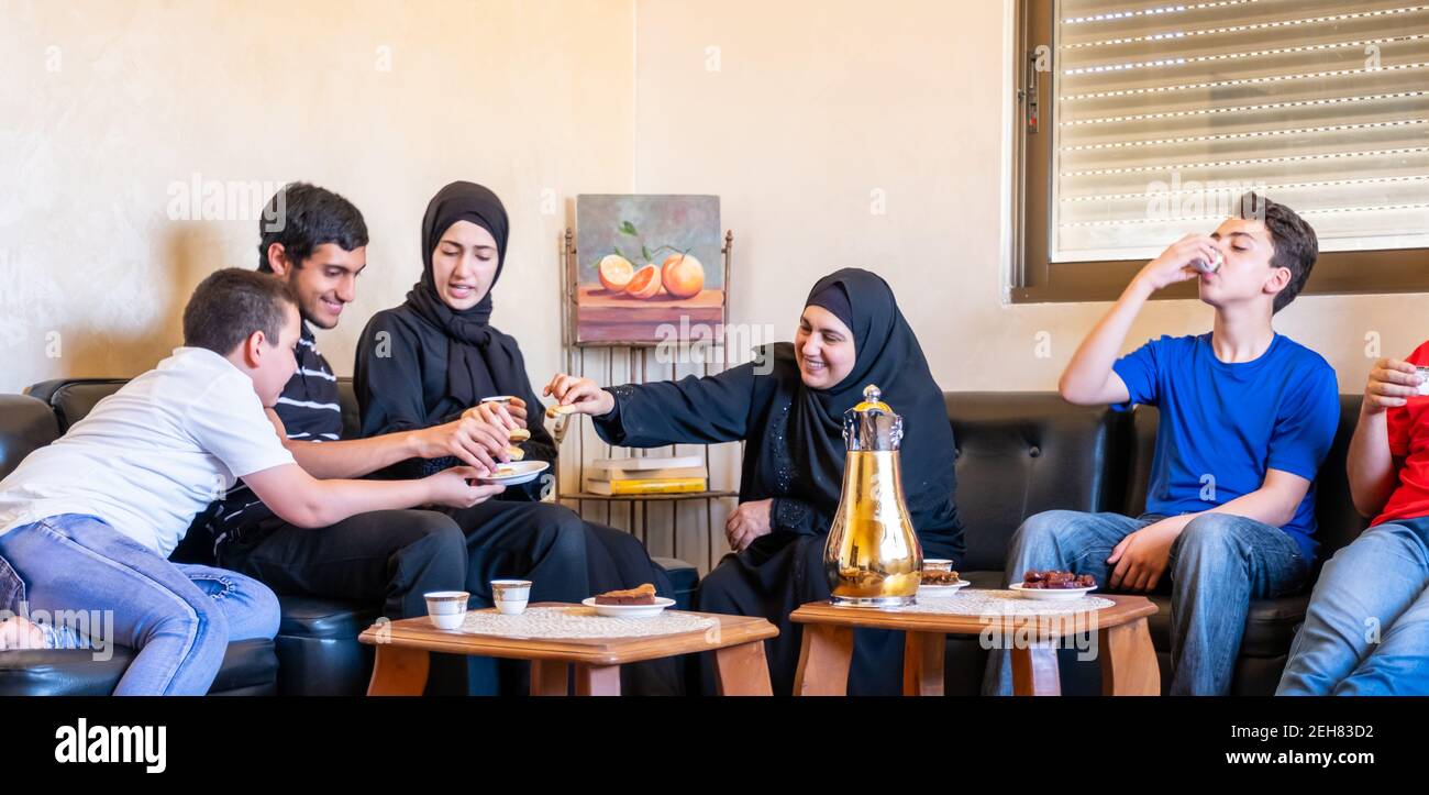 Happy Arabic family sitting together enjoying Arabic coffee and sweets ...