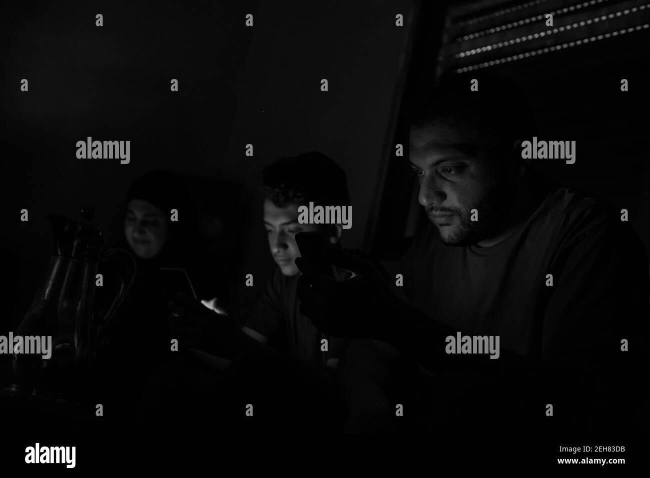 boys sitting in dark rooms on their smartphones using the internet ...