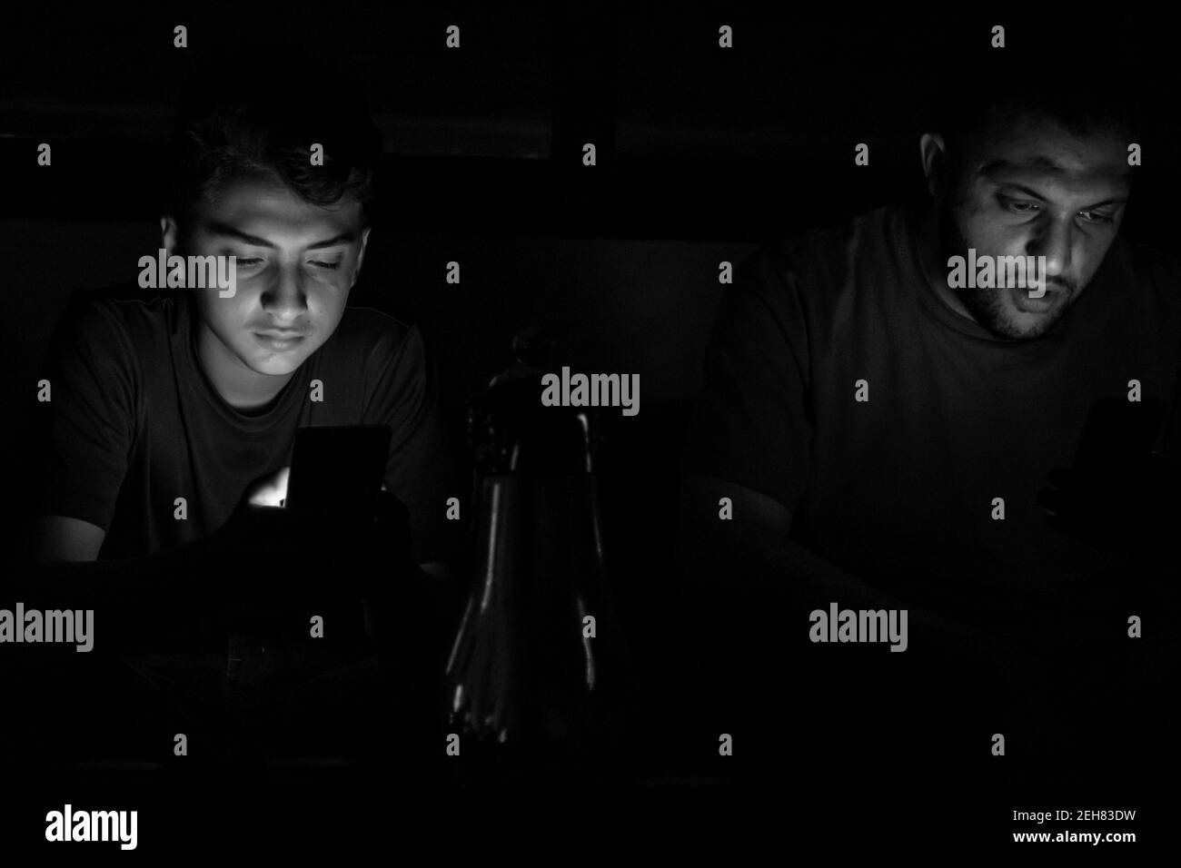 boys sitting in dark rooms on their smartphones using the internet ...