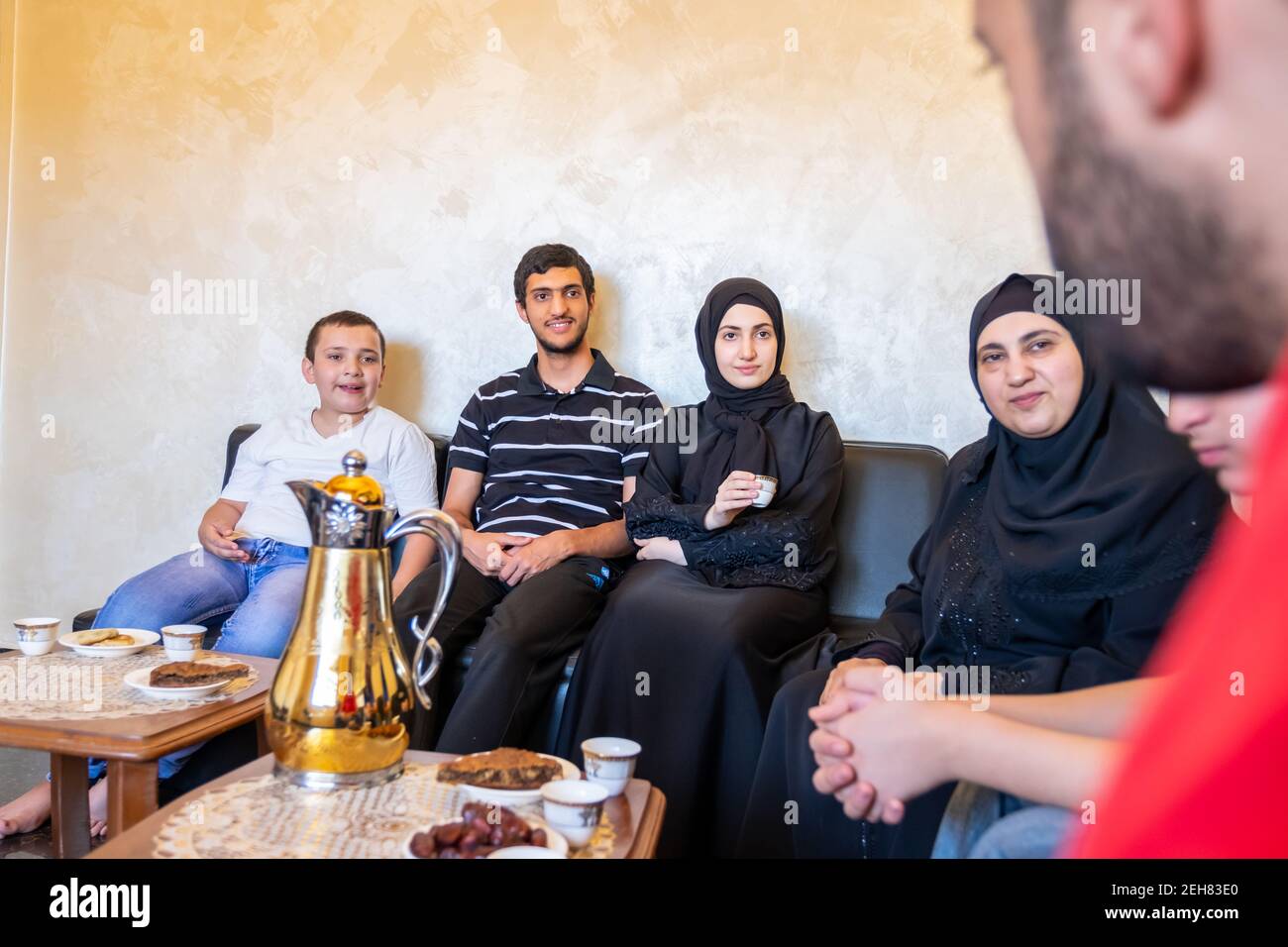 Happy Arabic family sitting together enjoying Arabic coffee and sweets ...