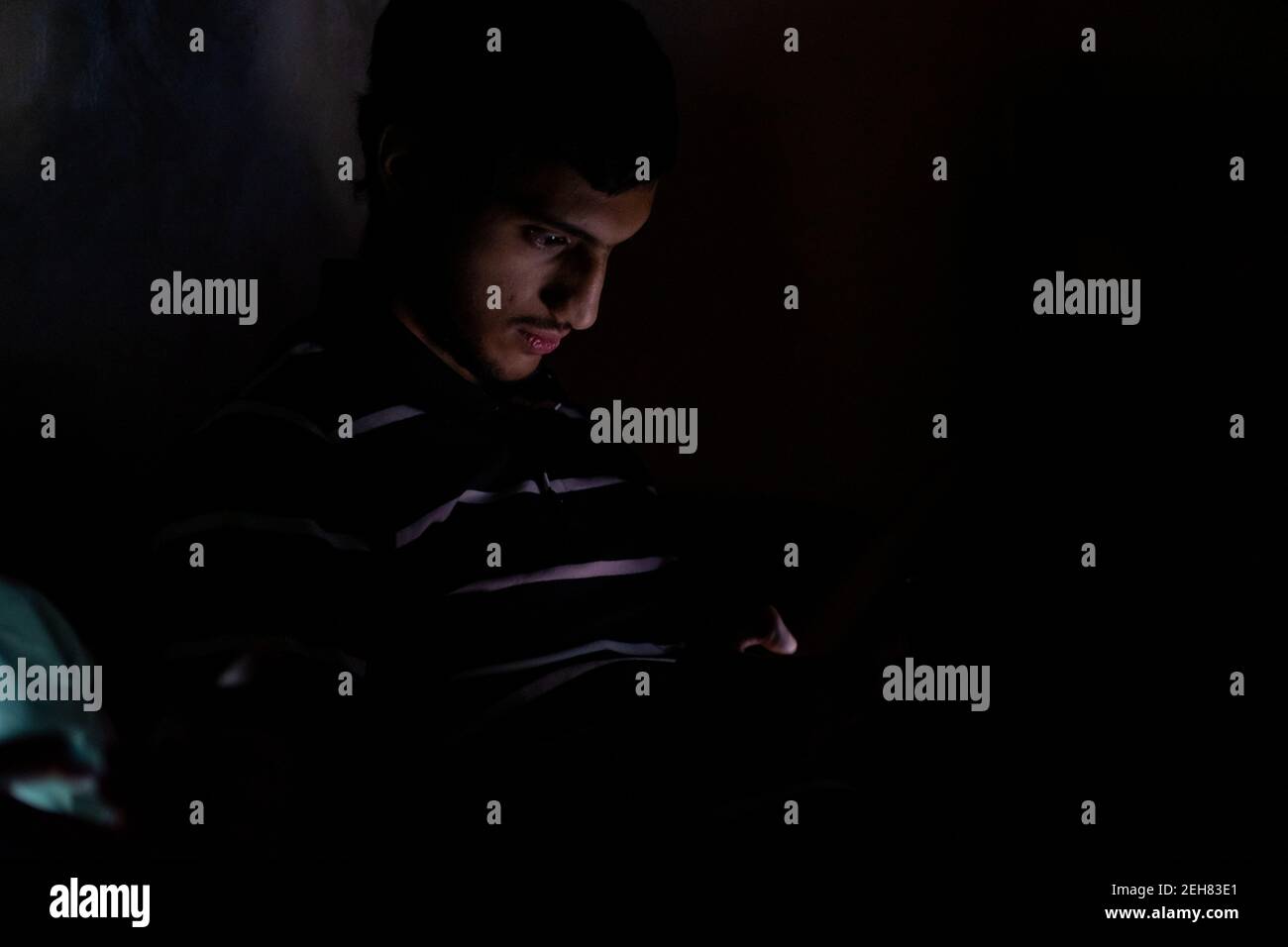 boys sitting in dark rooms on their smartphones using the internet ...