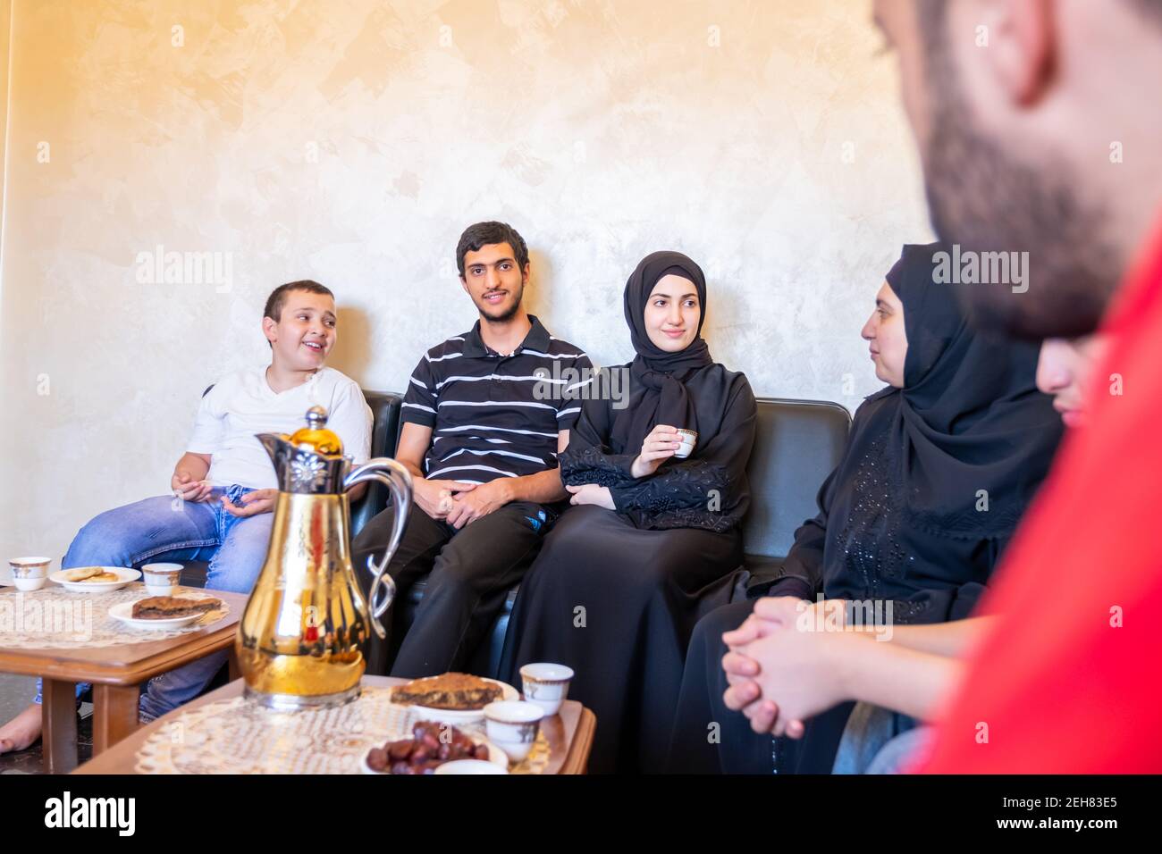 Happy Arabic family sitting together enjoying Arabic coffee and sweets ...