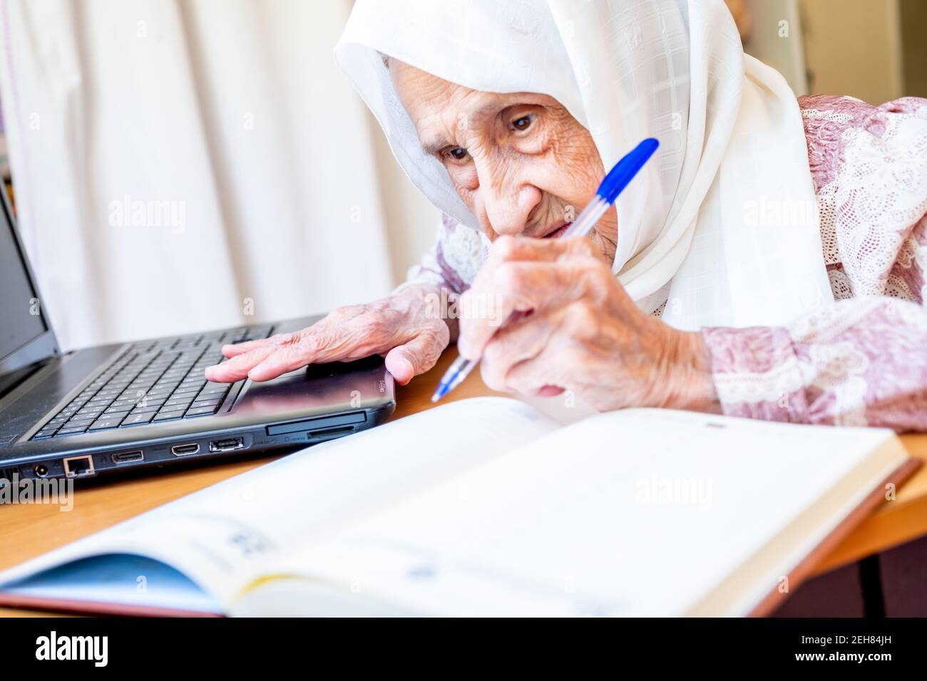 Old women studying and writing using laptop and notebook Stock Photo ...