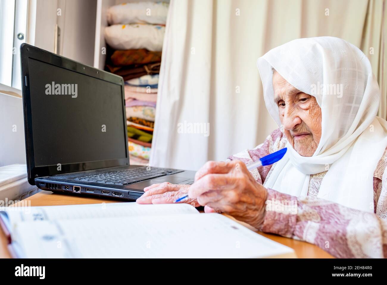 Old women studying and writing using laptop and notebook Stock Photo ...