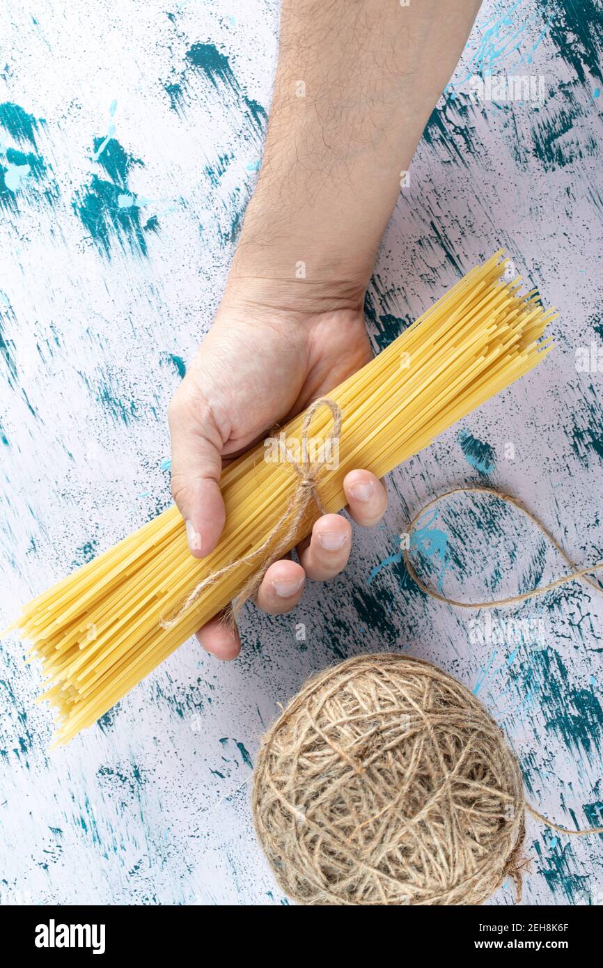 Male hand holding spaghetti pasta on colorful surface Stock Photo - Alamy