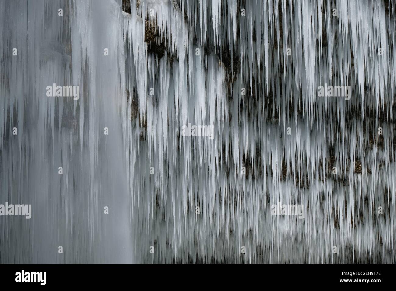 Beautiful long icicles of a frozen waterfall. Water flowing and ...